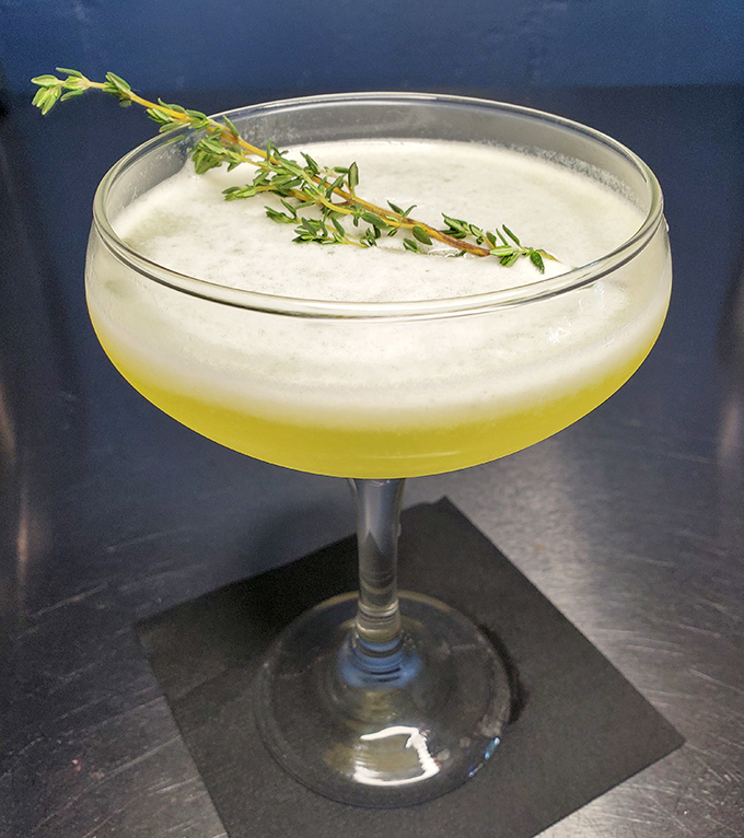 This isn't just a cocktail—it's a vacation in a glass, complete with a sprig of thyme that's dressed up and ready for its close-up.