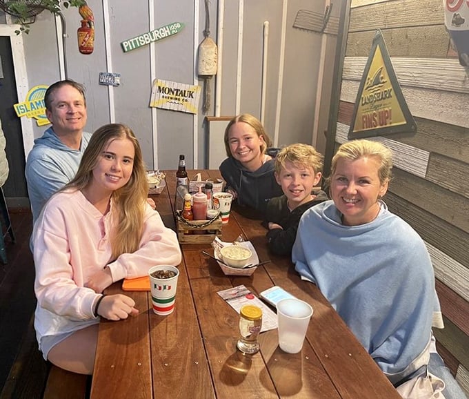 Happy diners gathered around a rustic wooden table, creating the kind of vacation memories that will outlast their sunburns and souvenir t-shirts.