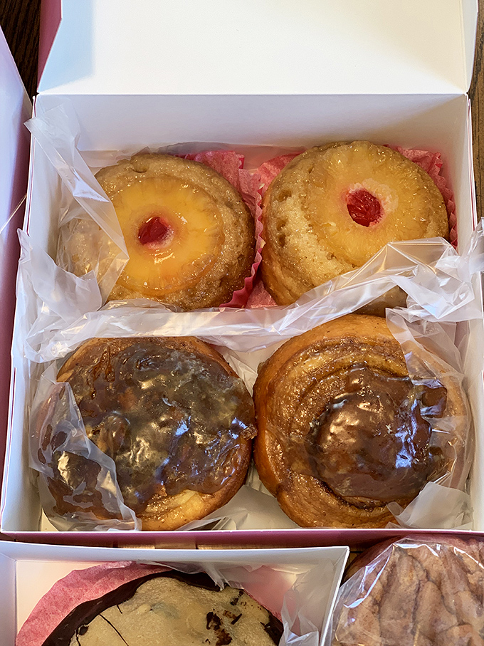 A box of donuts arranged like a delicious color wheel of possibilities. The pineapple upside-down versions are practically begging for a coffee companion.