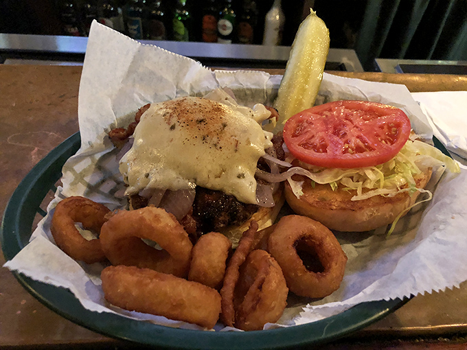 This burger with its melty cheese blanket and crispy onion rings isn't just food &ndash; it's therapy on a plate. The pickle stands guard like a tangy sentinel.
