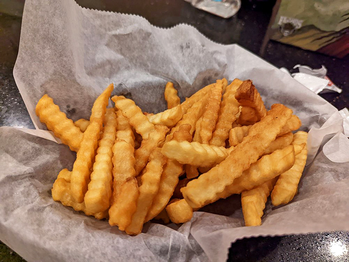 Golden, crispy crinkle-cut fries nestled in paper &ndash; the perfect sidekick to any sandwich adventure, no cape required.