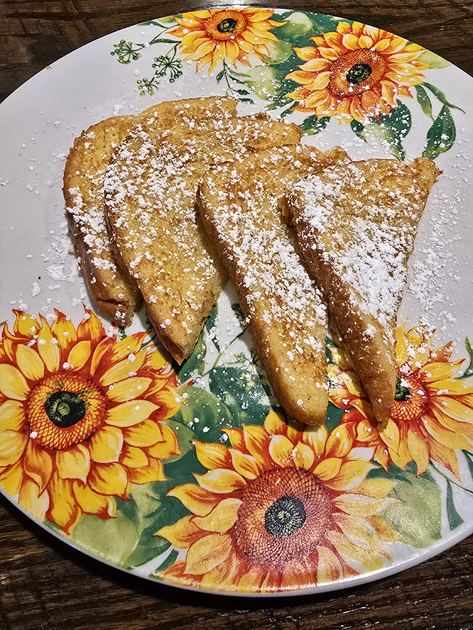 French toast dusted with powdered sugar on a sunflower plate&mdash;breakfast that makes you feel like you're eating at grandma's house, if grandma were a culinary genius.