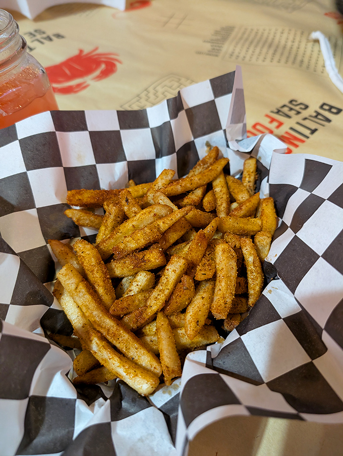 These perfectly seasoned fries arrive in checkered paper boats, ready to sail straight into your happy heart.