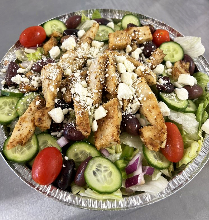 A Greek salad that doesn't skimp on the good stuff—olives, feta, and seasoned chicken arranged like edible artwork.