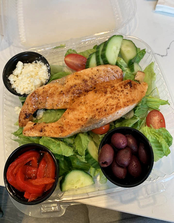 A Mediterranean vacation on a plate: perfectly grilled salmon perched atop crisp greens with feta, olives, and roasted peppers that would make Poseidon himself order seconds.