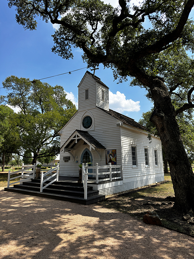 The charming white chapel stands sentinel under ancient oaks, a postcard-perfect slice of small-town Texas heritage.