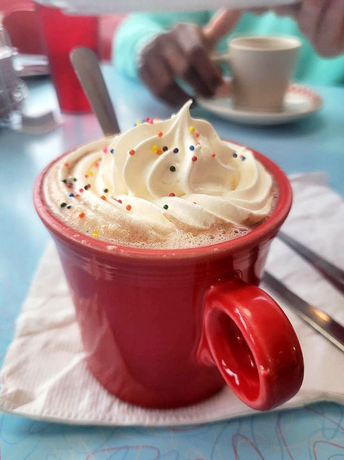 Hot chocolate crowned with whipped cream and sprinkles&mdash;proof that sometimes the best part of adulting is ordering dessert for breakfast. 