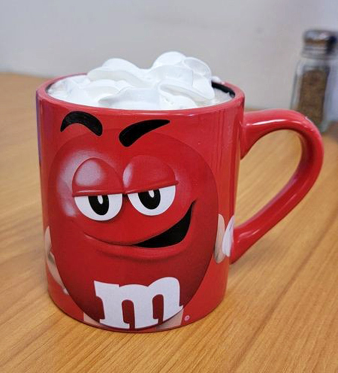Hot chocolate served with whipped cream in an M&M's mug – because sometimes adulthood means choosing joy over matching dinnerware.