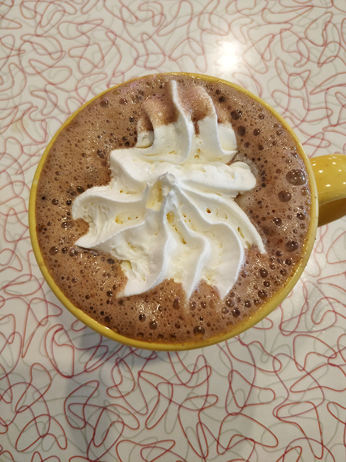Hot chocolate elevated to an art form, with whipped cream swirled like a cloud and served in a sunshine-yellow mug that brightens even the grayest Ohio day.