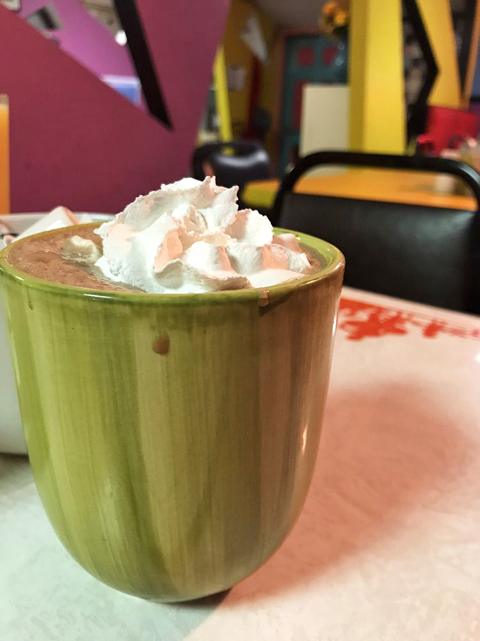 Hot chocolate served in a distinctive green mug with a cloud of whipped cream&mdash;the perfect companion for Erie's chilly mornings.