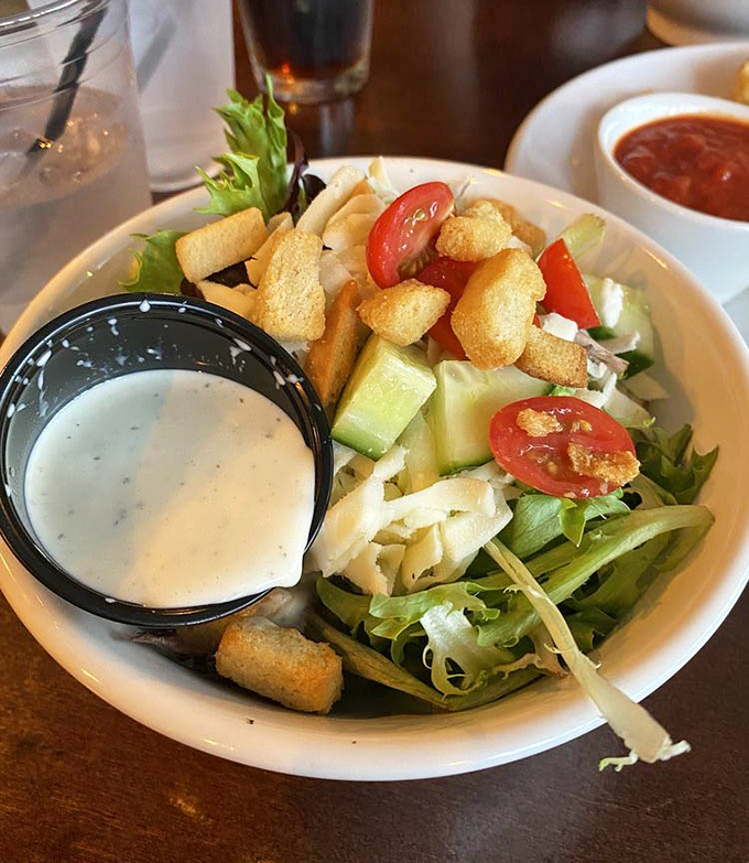 A house salad that actually deserves your attention. Crisp greens, fresh tomatoes, and those croutons&mdash;the supporting actors who secretly steal the show.