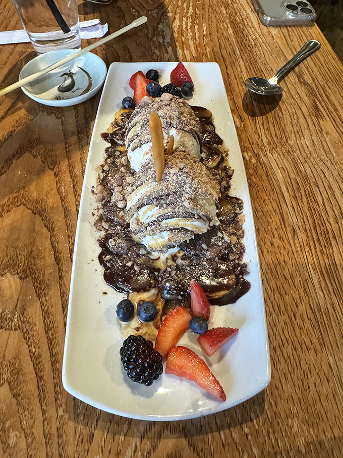 A dessert that doesn't whisper "indulgence" but shouts it - ice cream nestled among berries and chocolate, like a sweet island paradise.