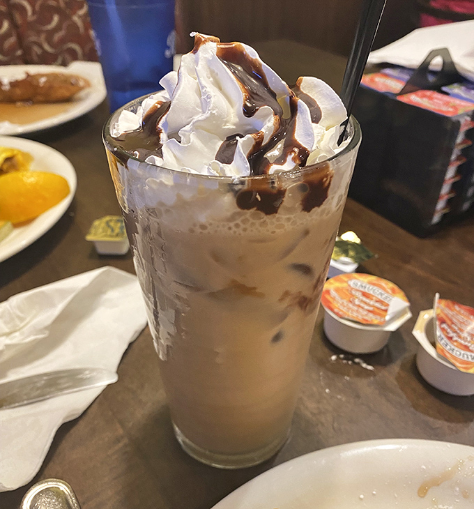 An iced coffee crowned with whipped cream and chocolate drizzle that makes your regular morning caffeine fix look like it needs therapy.