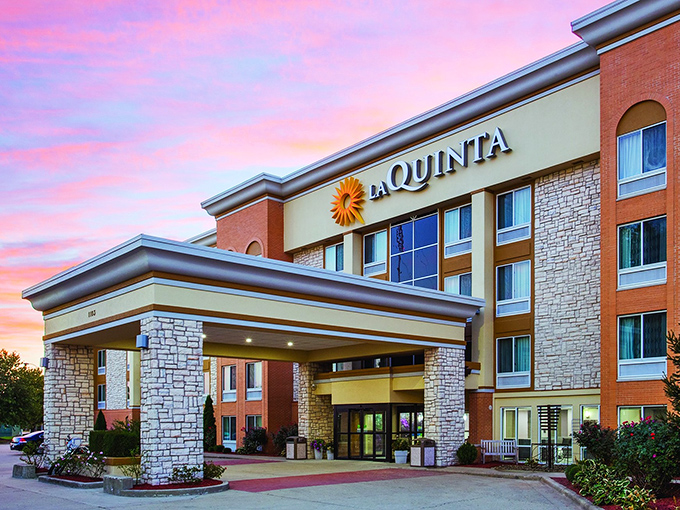 La Quinta's sunset-kissed facade offers weary travelers the golden promise of clean sheets and continental breakfast&mdash;the unsung heroes of any road trip.