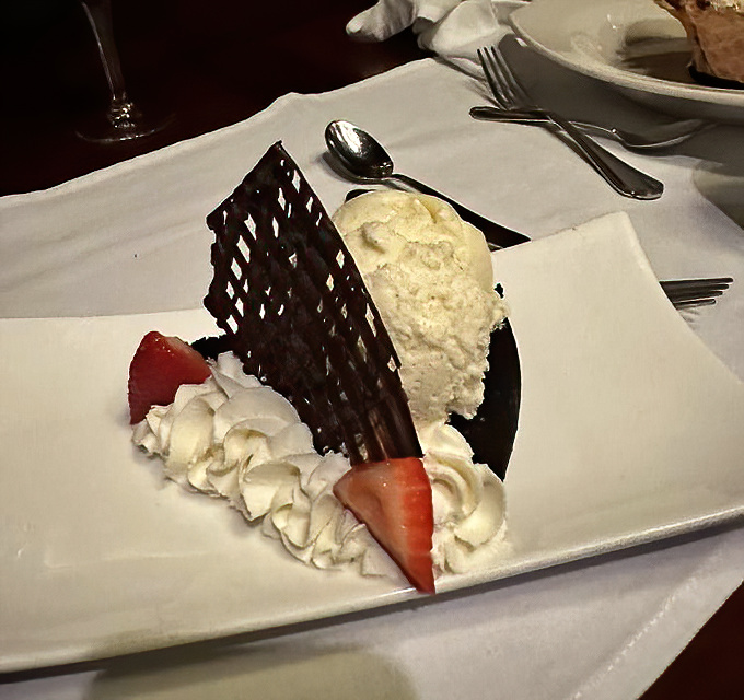 Architectural dessert brilliance: chocolate lattice standing guard over cream and berries like the world's most delicious security system.