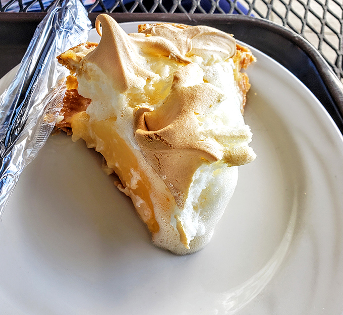 Lemon meringue pie with peaks so perfect they deserve their own topographical map. Cloud-like meringue hiding zesty sunshine below.