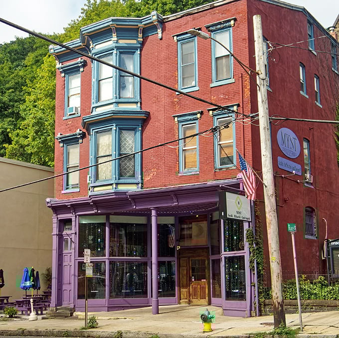 MYST's purple storefront pops against the brick like a royal visitor in a working-class neighborhood. Those bay windows have been people-watching for over a century.