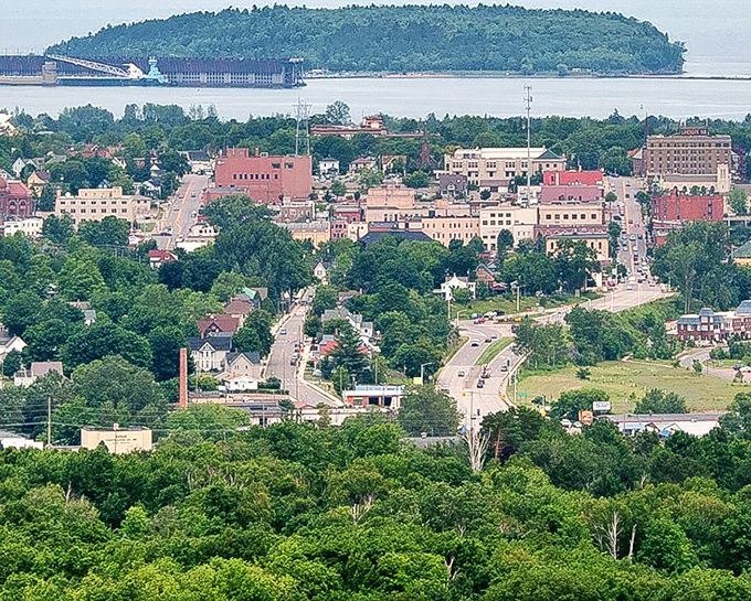 Marquette unfolds toward Lake Superior's vastness, its downtown buildings nestled between lush greenery and the world's largest freshwater lake.