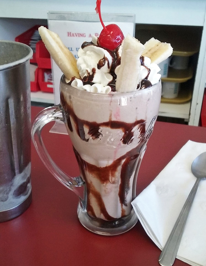 This isn't just a milkshake&mdash;it's dessert architecture. Bananas, whipped cream, and chocolate drizzle create a tower of happiness in a glass mug.