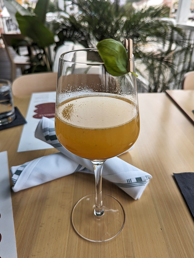 A mimosa garnished with fresh basil—because sometimes breakfast deserves a cocktail that's putting in as much effort as you did getting out of bed.