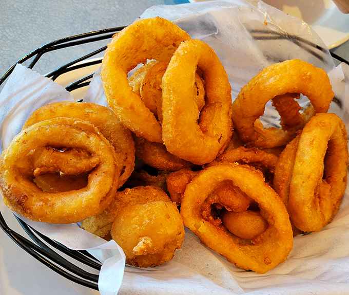 Golden onion rings arrive crispy and irresistible, forming perfect circles of fried bliss that disappear way too quickly.