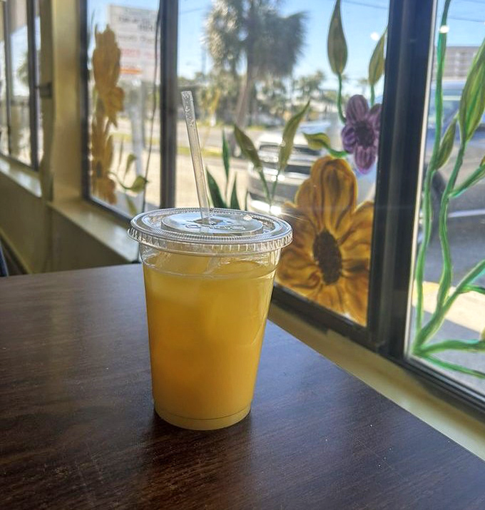 Fresh-squeezed orange juice by a window painted with sunflowers. Florida sunshine in liquid form, no SPF required.