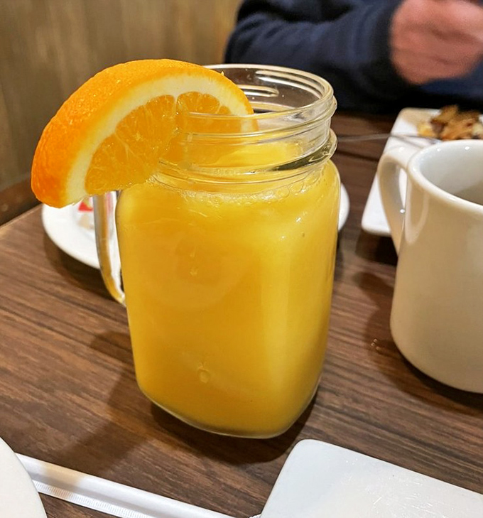 Fresh-squeezed orange juice served in a mason jar with an orange slice garnish &ndash; liquid sunshine to brighten your morning.