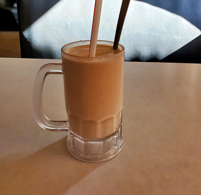 The chocolate shake arrives in its frosty mug throne, thick enough to require serious straw commitment and patience.