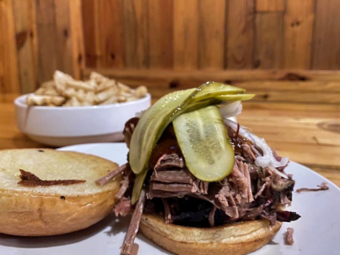 The pulled pork sandwich—where smoke-kissed meat meets pickle crunch in a handheld miracle that makes napkins absolutely necessary.