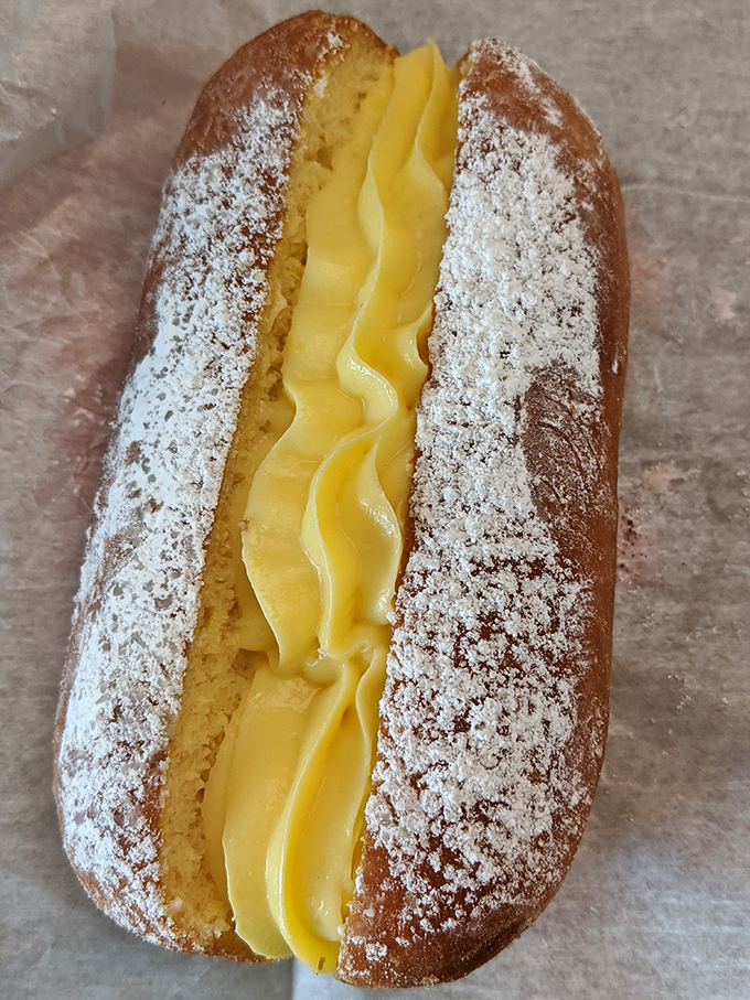 This custard-filled delight nestled between powdered sugar-dusted pastry isn't just dessert—it's what happiness would look like if it took physical form.