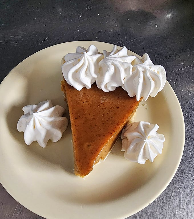 A slice of pumpkin pie that whispers "you deserve this" with every bite, crowned with whipped cream clouds of pure joy.