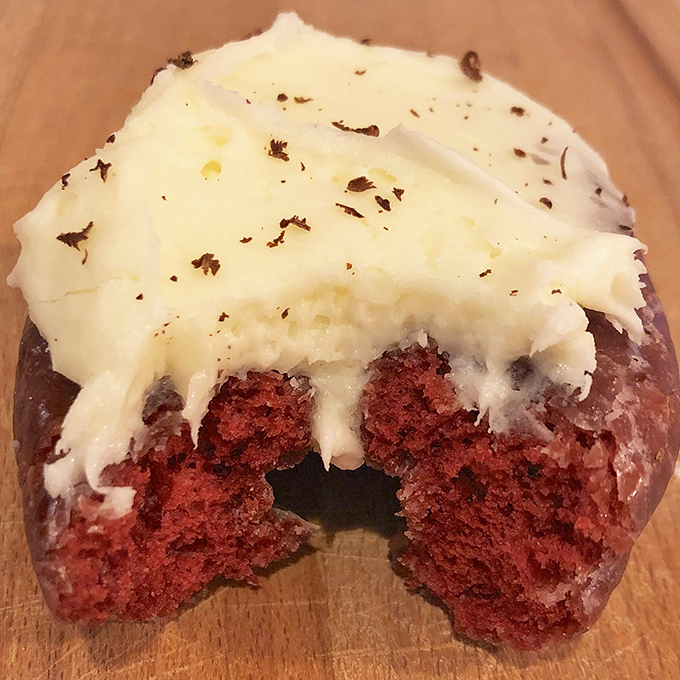 A red velvet donut with cream cheese frosting that would make your grandmother weep with joy. Half-eaten because no one has that much willpower.