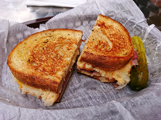 The Reuben, perfectly grilled and cut with surgical precision, revealing that magical intersection where corned beef, Swiss, and sauerkraut become something greater than their parts.