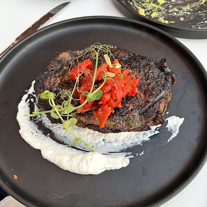 This ribeye doesn't just sit on the plate—it commands it, with a smoky char giving way to tender meat and a creamy sauce that's begging to be swiped.