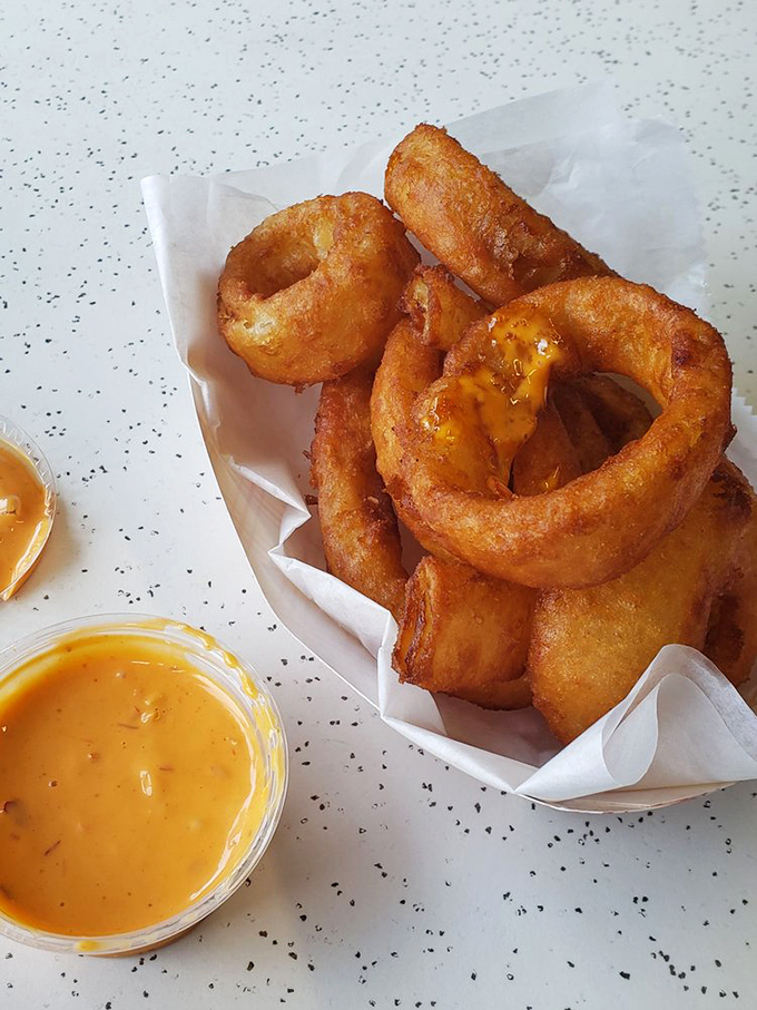 Golden onion rings with that perfect crunch-to-softness ratio, paired with cheese sauce that's practically begging for a dip.