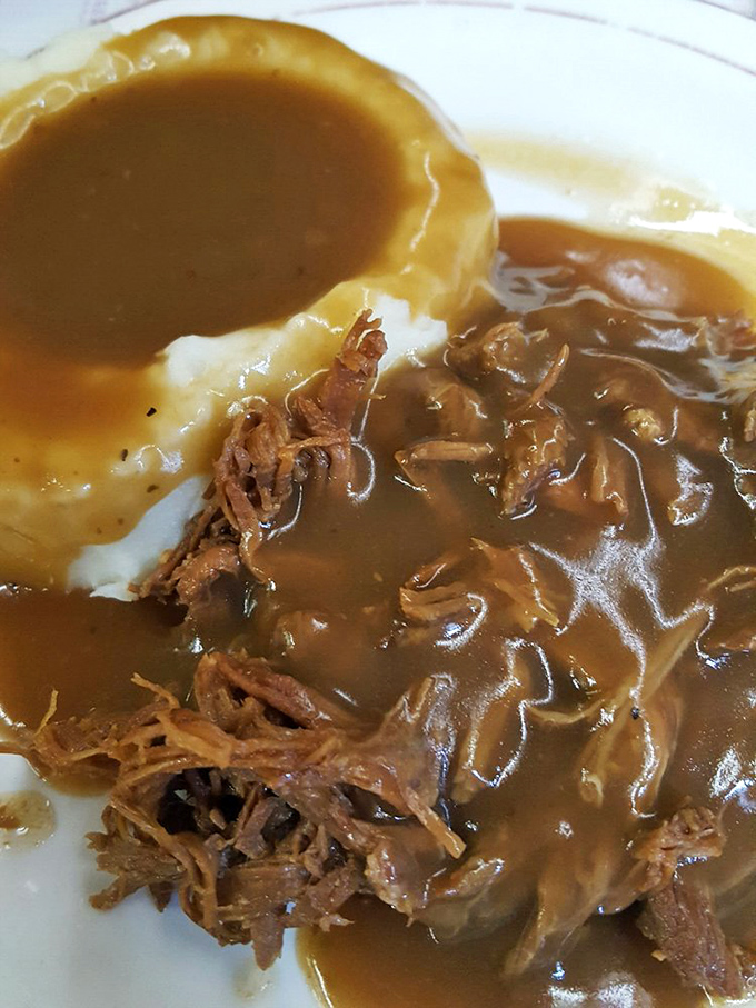 Roast beef that surrenders at the mere suggestion of your fork, nestled beside creamy mashed potatoes and swimming in gravy that should be bottled and sold as liquid happiness.