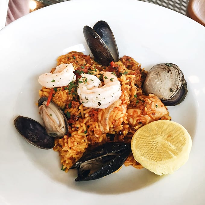 Seafood paella that transports you to coastal Spain, where each grain of saffron rice has absorbed a story from the sea.
