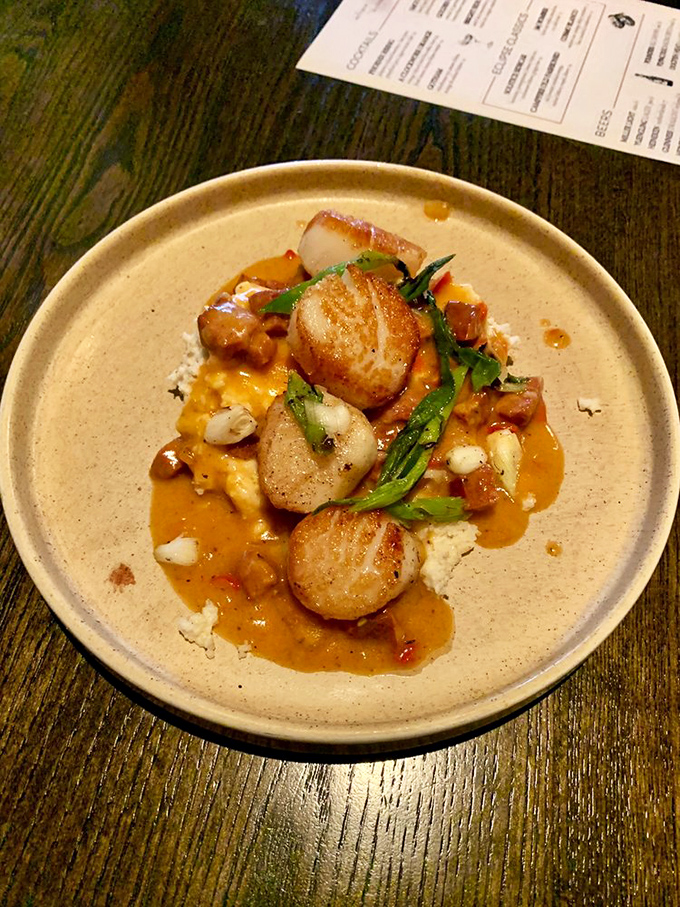 Scallops so perfectly seared they could make a French chef weep, nestled on a colorful bed that's part comfort food, part edible art.