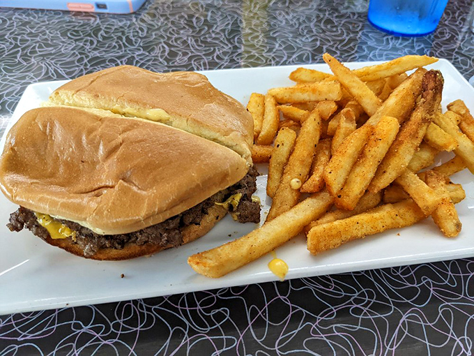 A classic smash burger with crispy fries represents everything great about unpretentious American diner cooking.