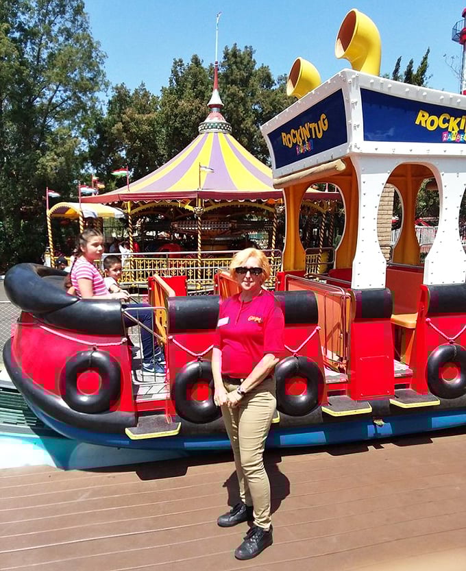 A cheerful ride operator stands ready at the Rockin' Tug attraction. These dedicated staff members are the unsung heroes of every memorable park visit.