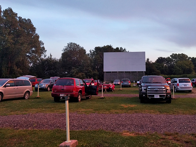 As twilight embraces the drive-in, vehicles settle in like modern-day covered wagons. The communal campfire of our time is a 40-foot screen.