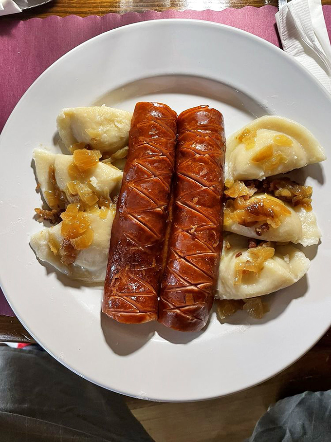 Kielbasa and pierogi sharing a plate like old friends at a reunion, with caramelized onions playing matchmaker. A Polish love story.