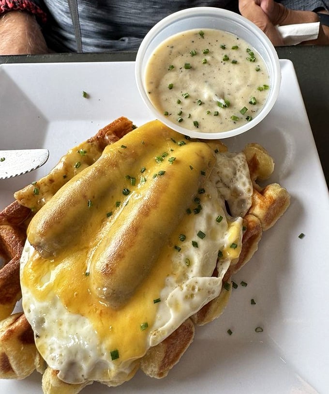 Savory breakfast perfection: melted cheese blankets this waffle creation while a side of herb gravy stands ready for dunking duty.
