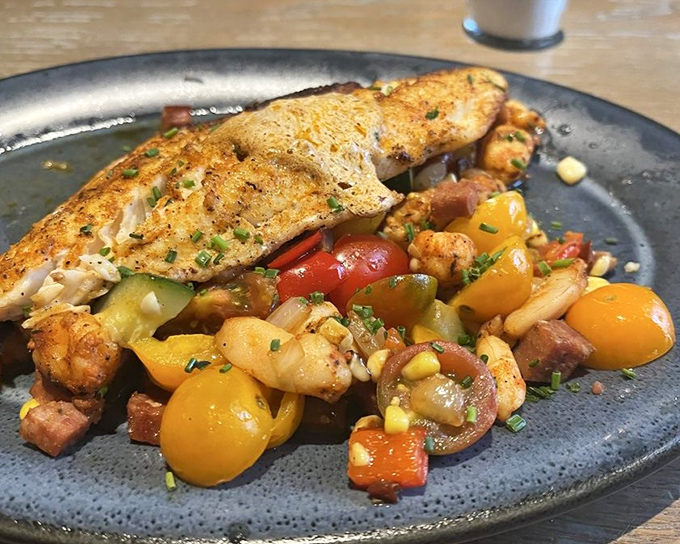 Fish so perfectly seared it practically has a suntan, resting on a colorful bed of summer vegetables that pop like edible confetti.
