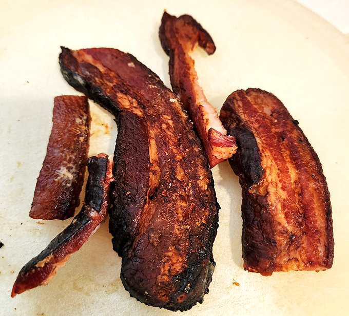 Oak-grilled bacon strips deliver smokiness that transforms breakfast into an event worth setting your alarm for early.
