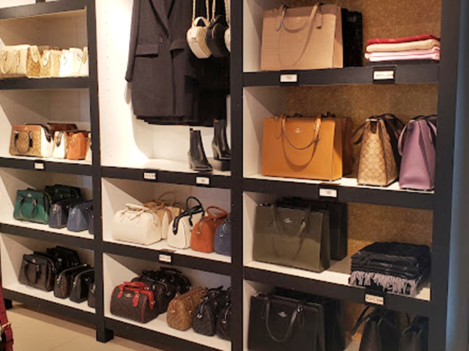 Handbag heaven arranged with museum-like precision – each purse silently promising to be the one that finally organizes your chaotic life.