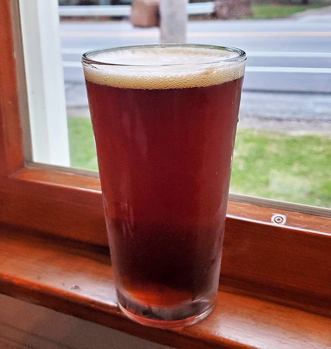 A perfectly poured amber brew catching window light &ndash; because sometimes the best companion to lake-fresh fish is a cold one with a view.