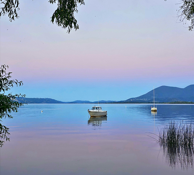 Twilight transforms Clear Lake into a canvas of purples and blues, with boats floating like brushstrokes on a watercolor masterpiece.