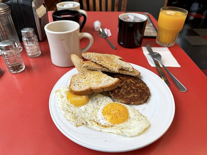 Two sunny-side-up eggs stare back at you like optimistic eyes, flanked by toast and a sausage patty that means serious breakfast business.