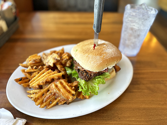 Not just a burger, but a hand-crafted monument to beef, complete with a knife standing proudly at attention like it's guarding deliciousness.